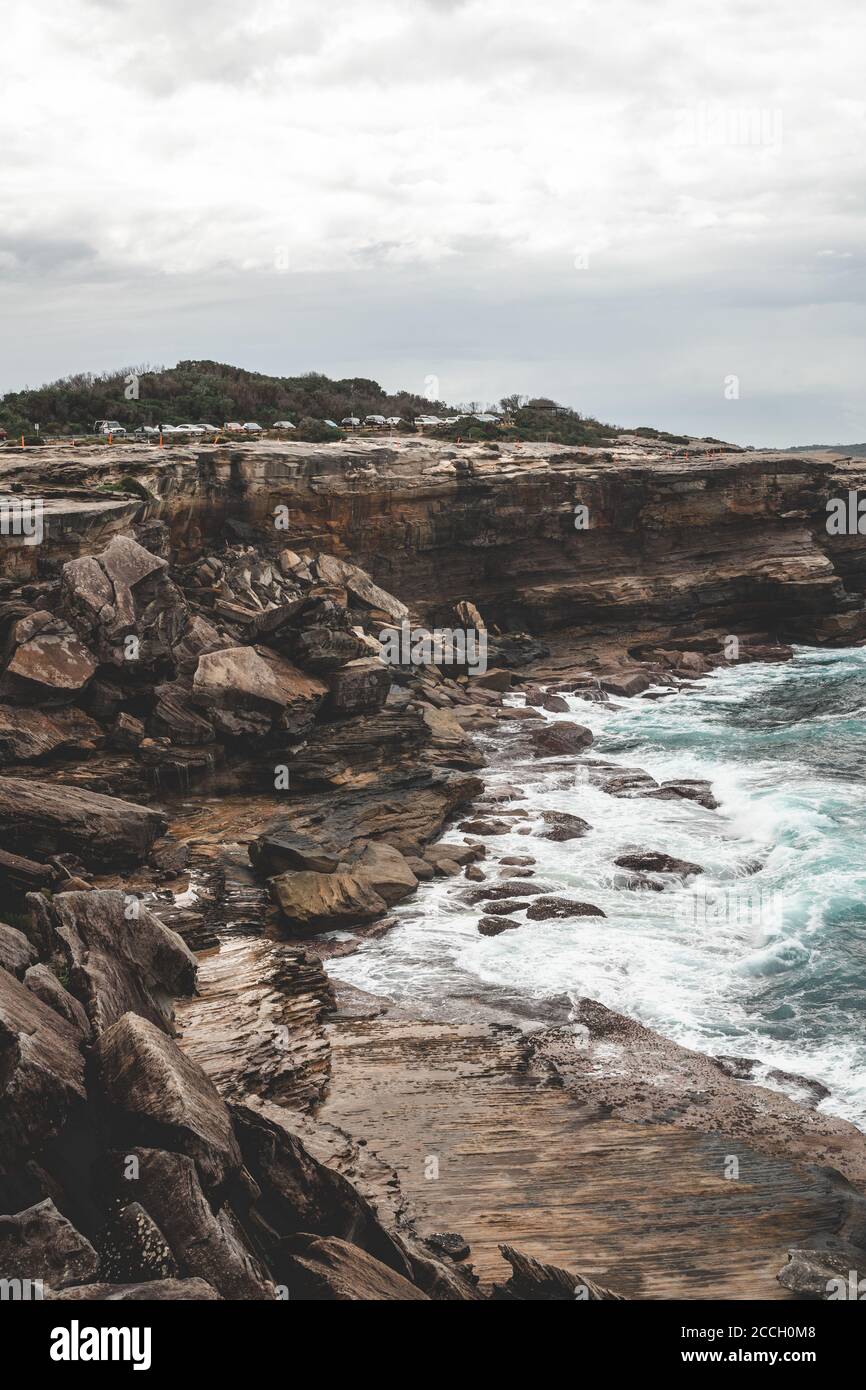 Beautiful vertical shot of a large cliff next to blue water on a gloomy ...