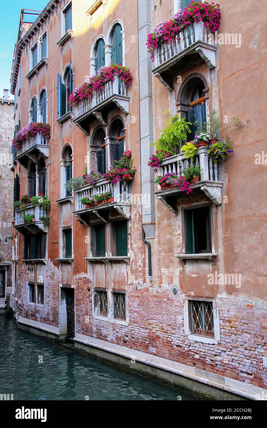 Building with flower boxes on the balconies in a narrow canal, Venice ...