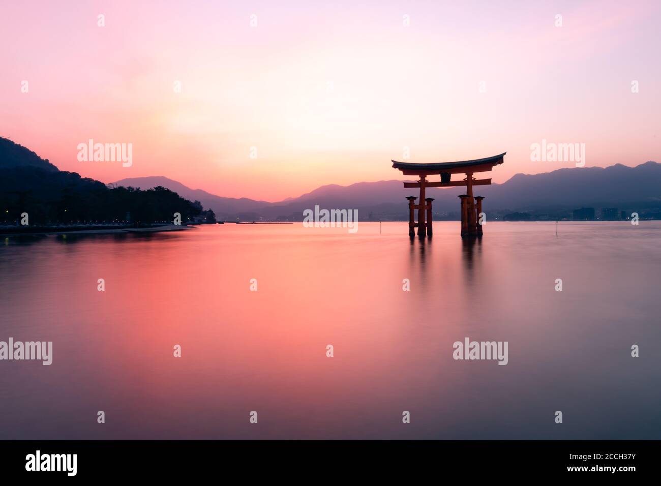 The sun sets behind the floating tori gate at Istukushima Shrine in ...