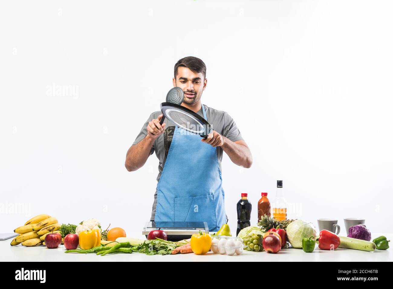 Handsome cheerful smiling indian man preparing meal in the kitchen ...