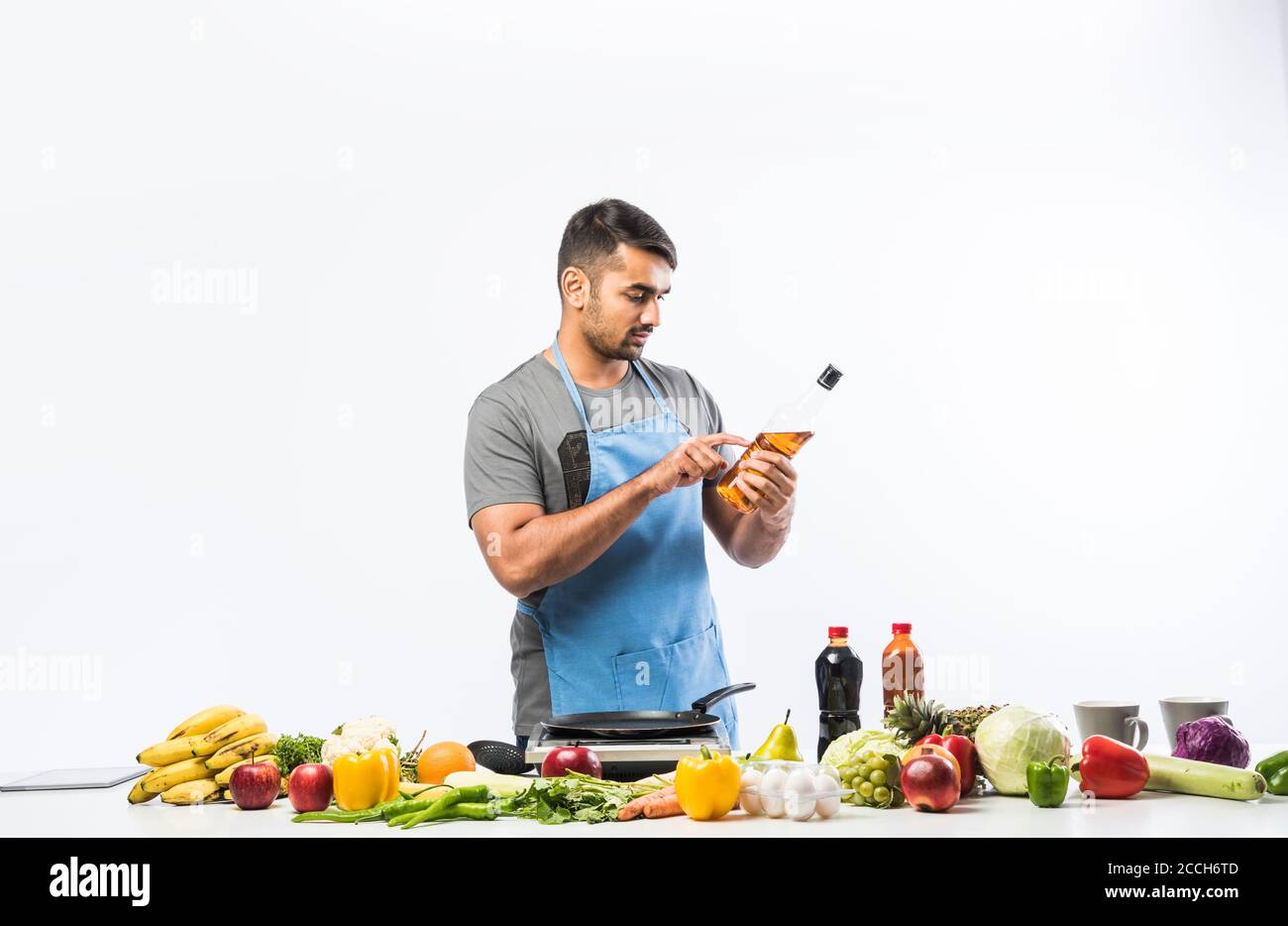 Handsome cheerful smiling indian man preparing meal in the kitchen ...