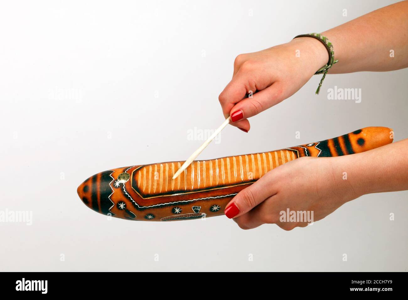 Highly decorated Gourd Guiro being played with a feather quill scraper ...