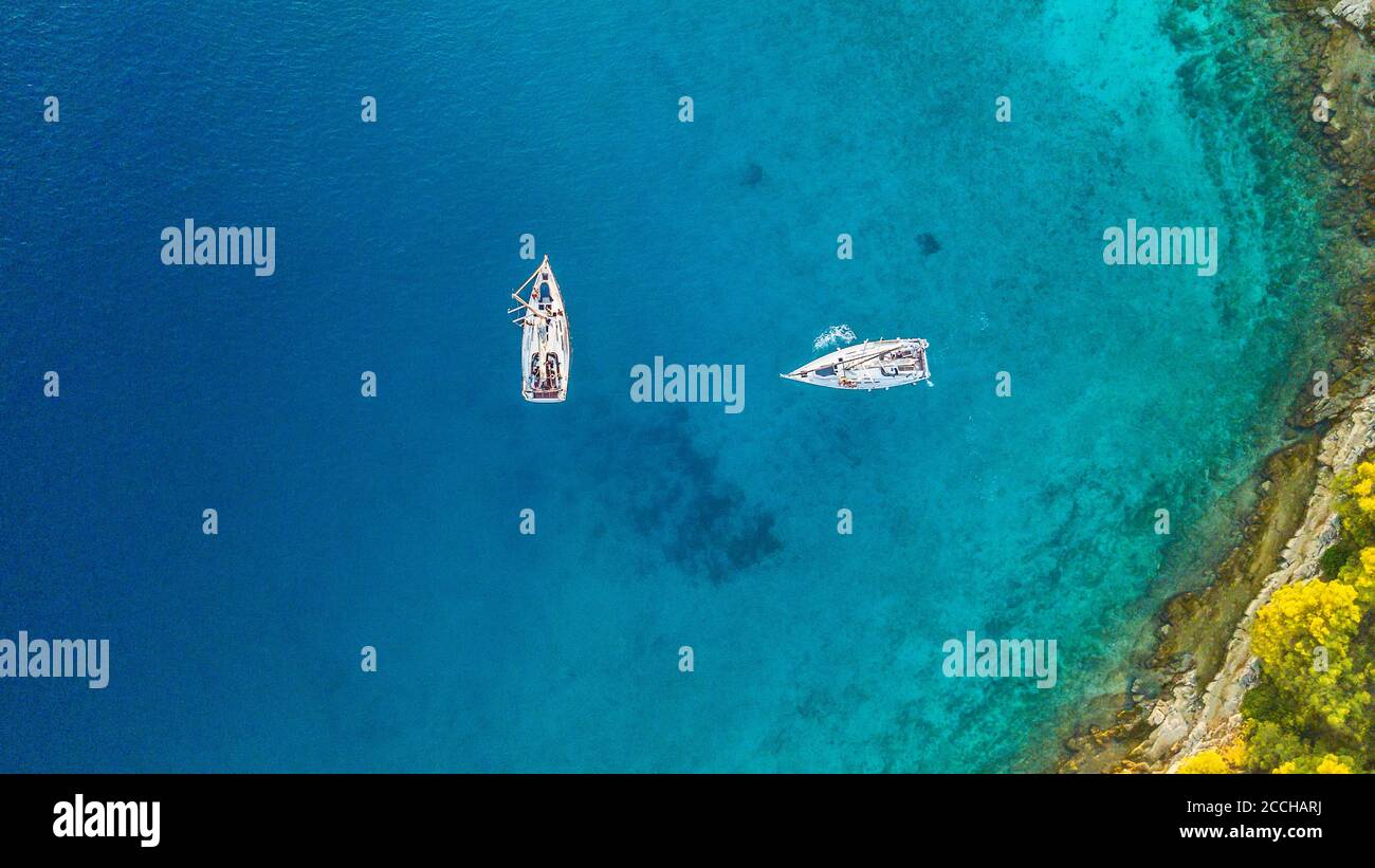 Aerial view of two sailing boats anchoring next to reef. Bird eye view ...