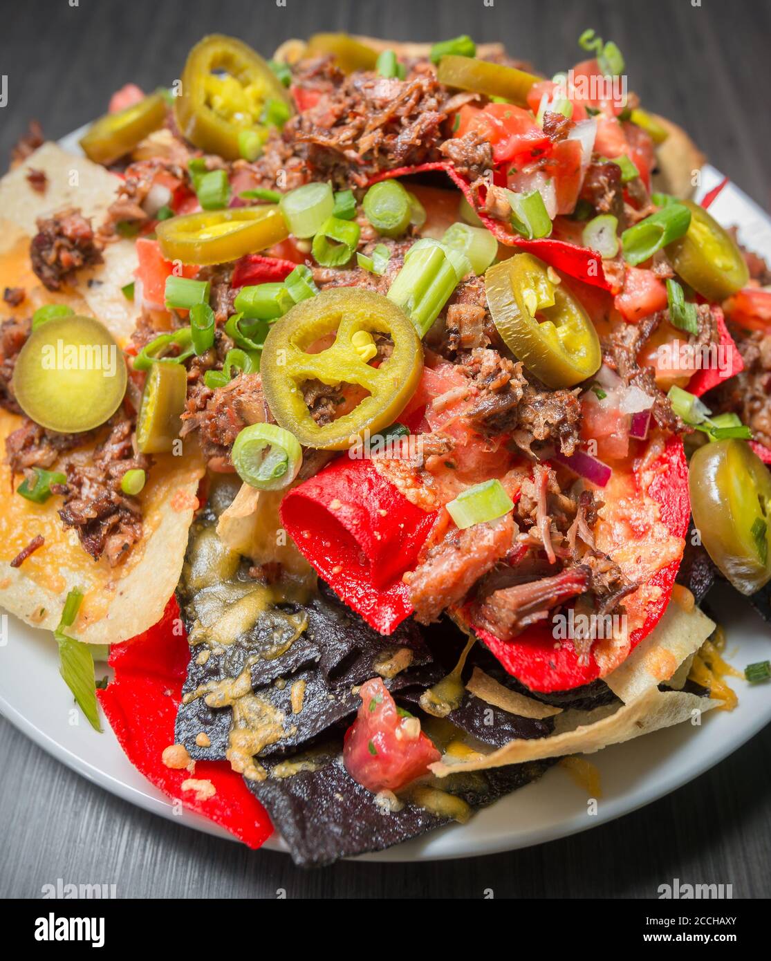 Closeup of a plate of burnt end beef brisket nachos with jalapeños and ...