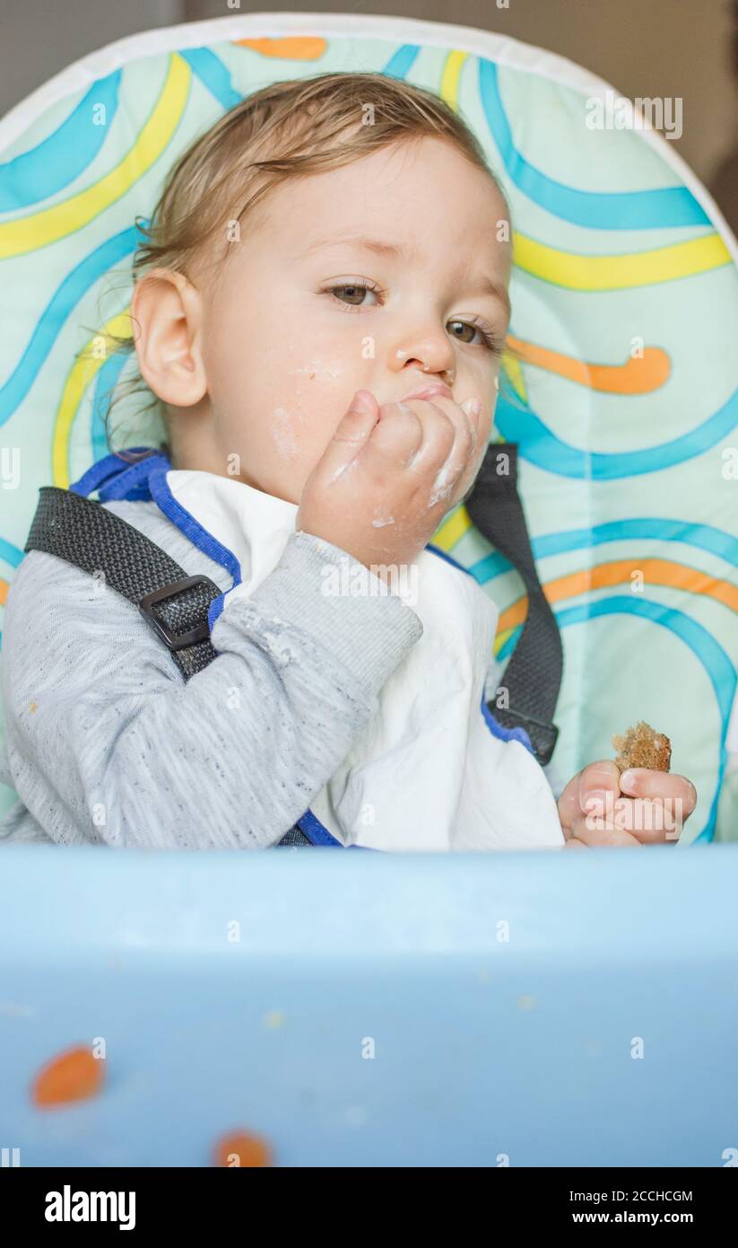 Cute baby child getting messy eating by itself Stock Photo - Alamy