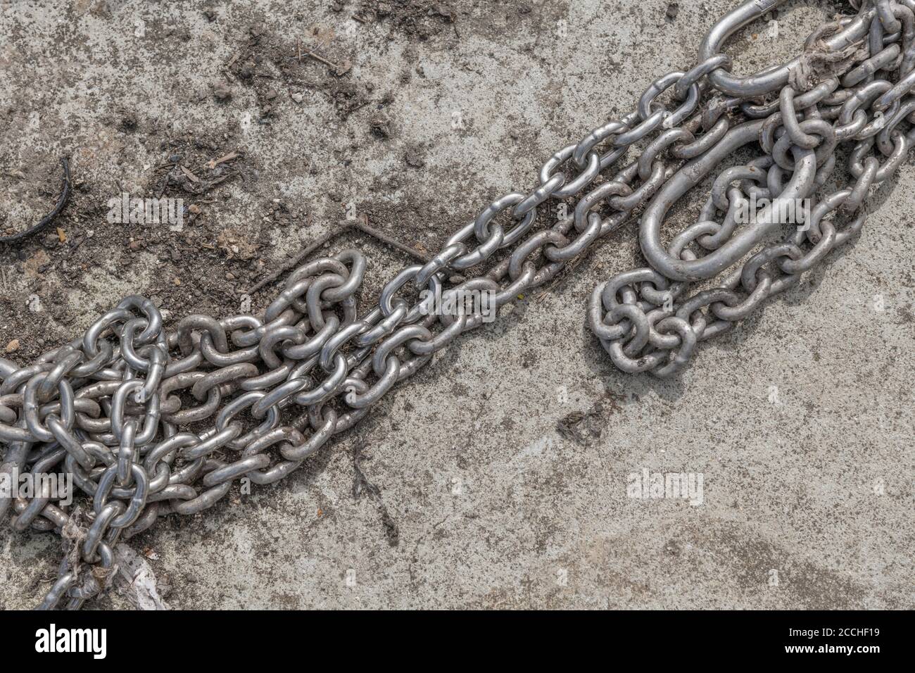 Industrial chain. Bright metal chain (?stainless steel) on concrete ...