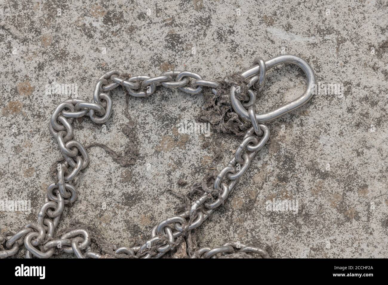 Industrial chain. Bright metal chain (?stainless steel) on concrete ...