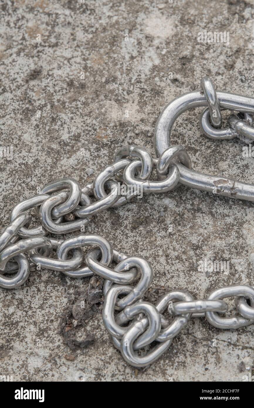 Industrial chain. Bright metal chain (?stainless steel) on concrete ...