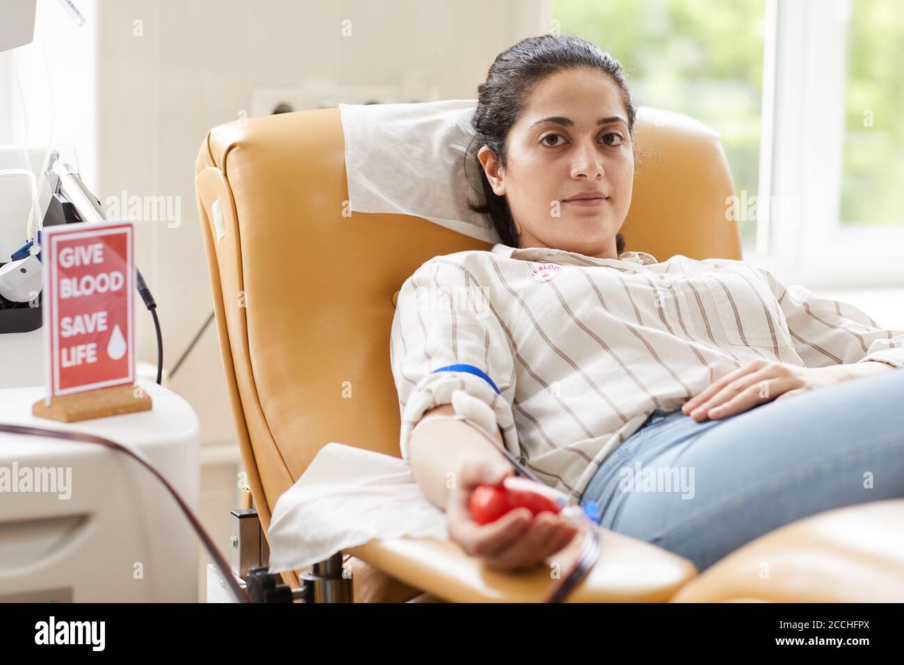 Portrait of female donor lying on the couch with catheter and looking ...