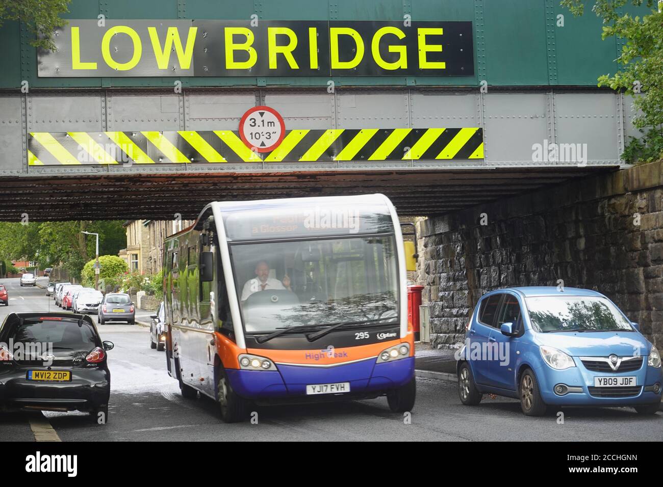 A single-decker bus passes under a low bridge in Glossop, Derbyshire ...