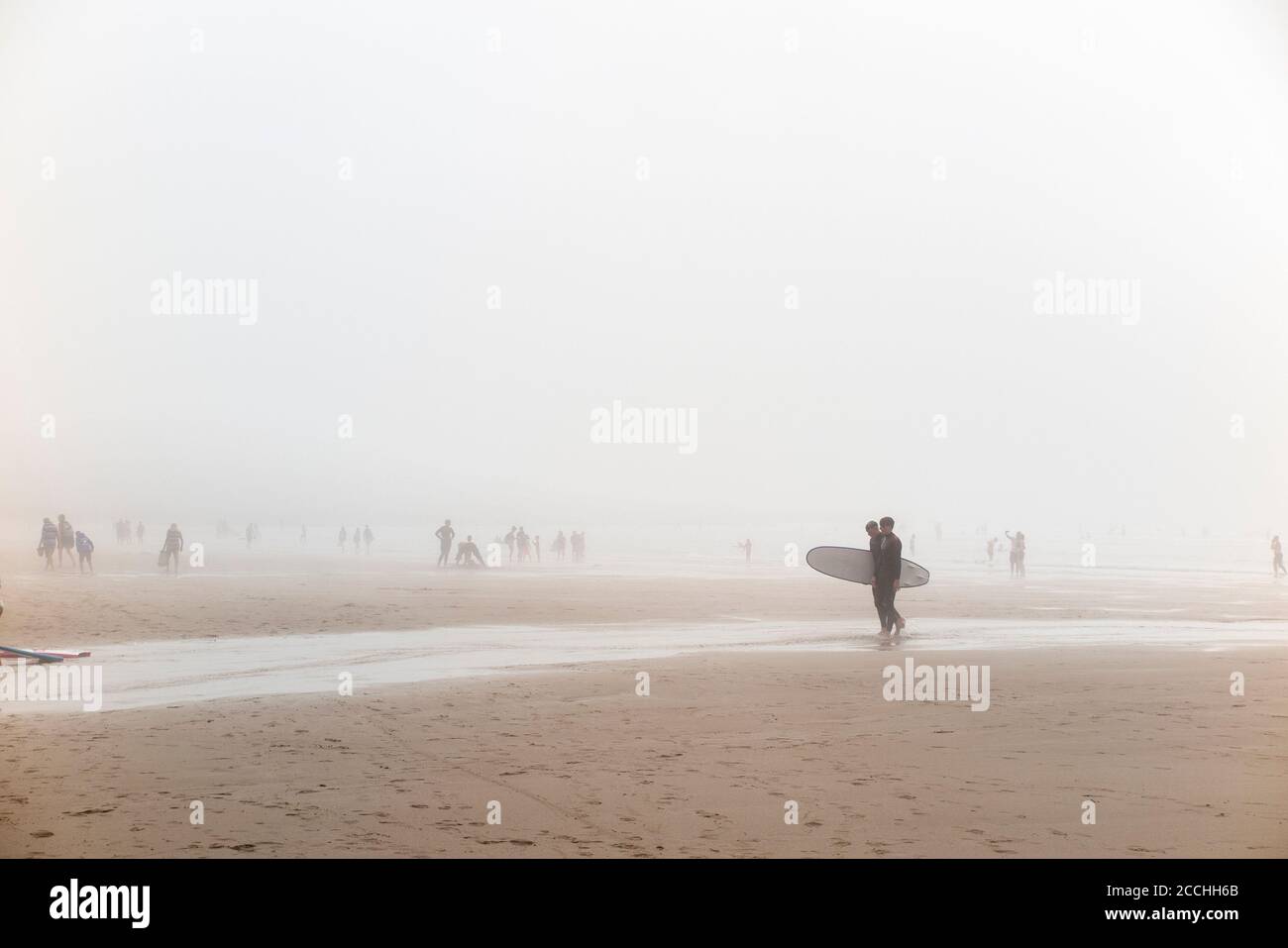 Two surfers on Croyde beach in a heavy sea mist Stock Photo - Alamy