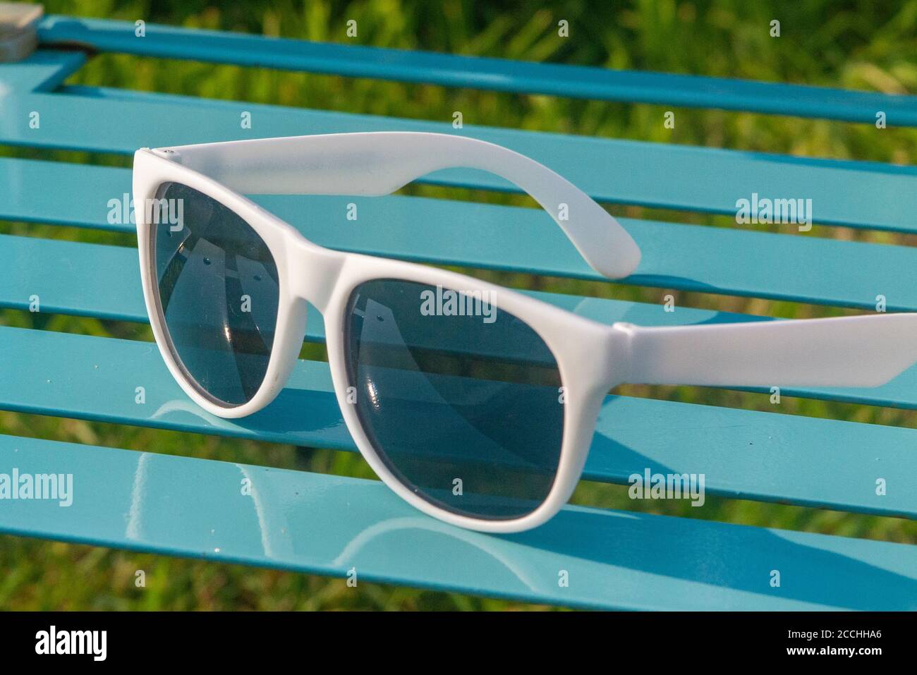 Some cool white framed glasses on a slatted blue chair Stock Photo - Alamy
