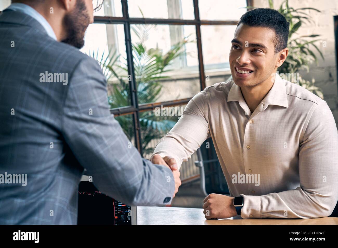 Two businessman making handshake gesture, sitting in office Stock Photo ...