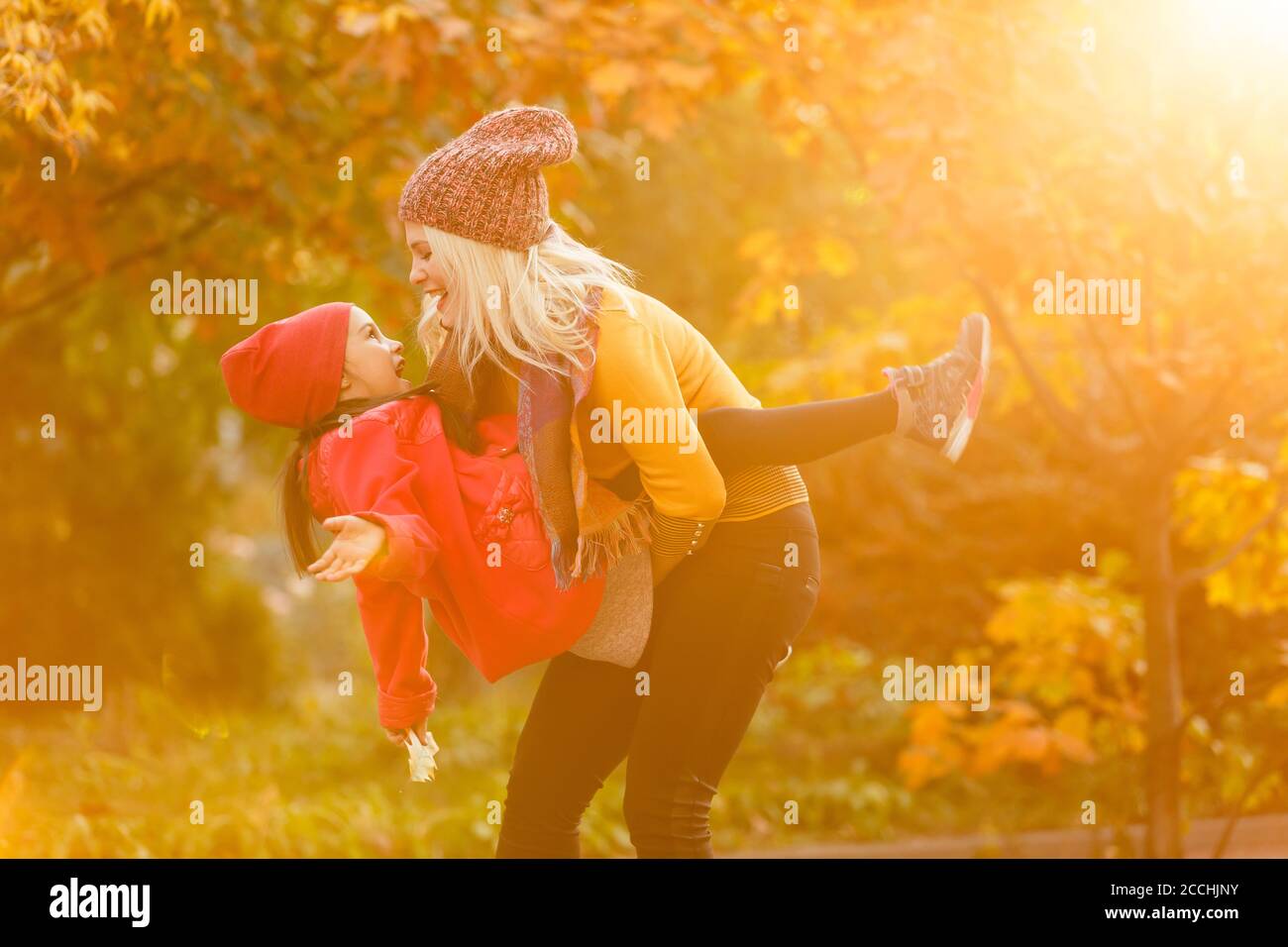 Mother giving daughter piggyback ride in autumn woodland Stock Photo ...