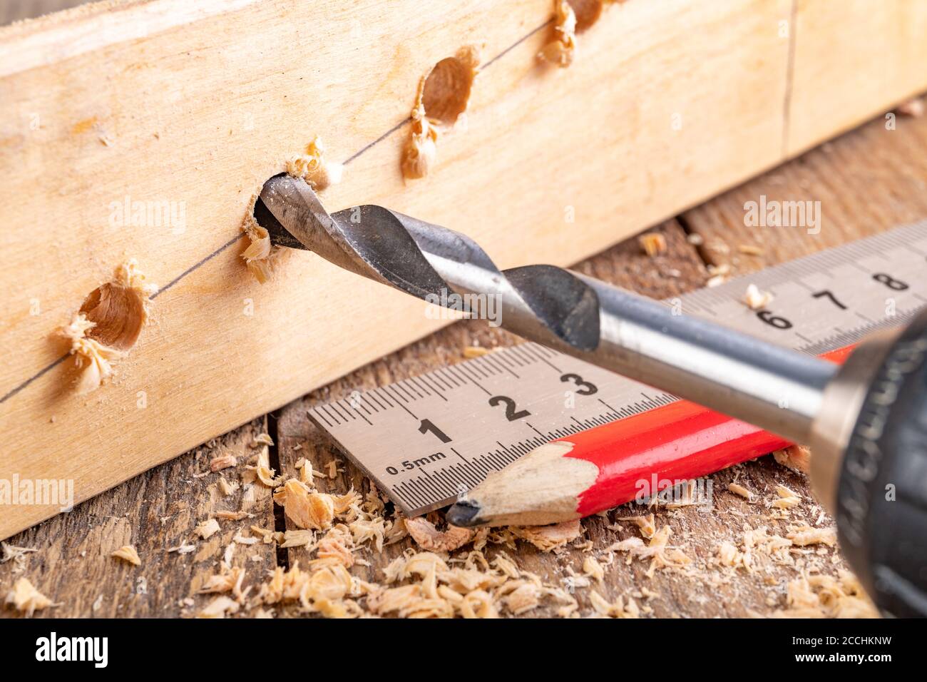 Creating holes with a metal drill in a piece of wood. Metal ruler for ...