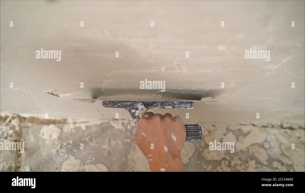 Cut the plaster on the wall with a spatula. Spatula on the wall. Hand ...