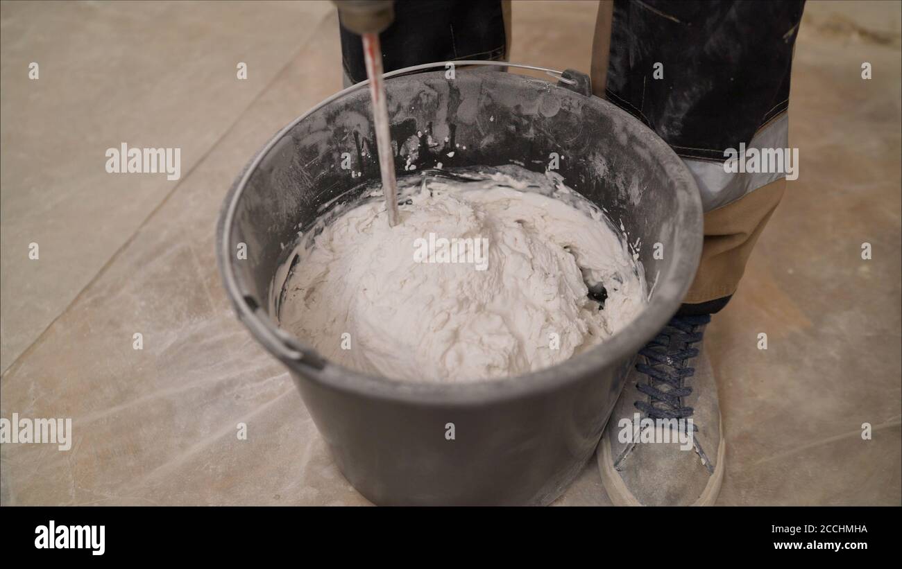Mix the mixture in a black bucket. Worker mixes a solution in a black ...