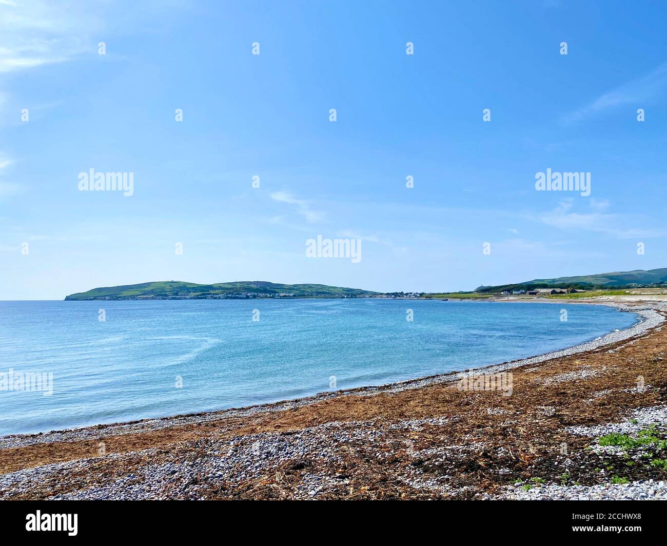 Looking across the pebble beach and sea towards the coastal town of ...