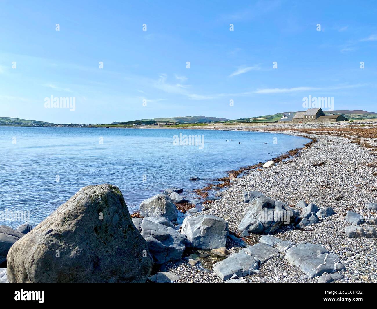 Looking across the pebble beach and sea towards the coastal town of ...