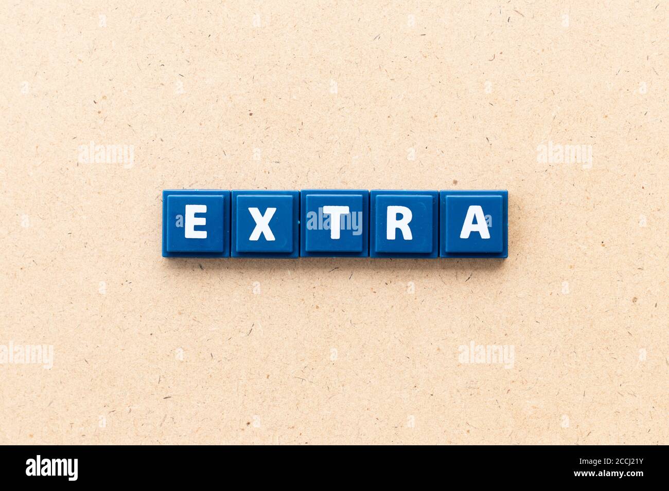 Tile letter in word extra on wood background Stock Photo - Alamy