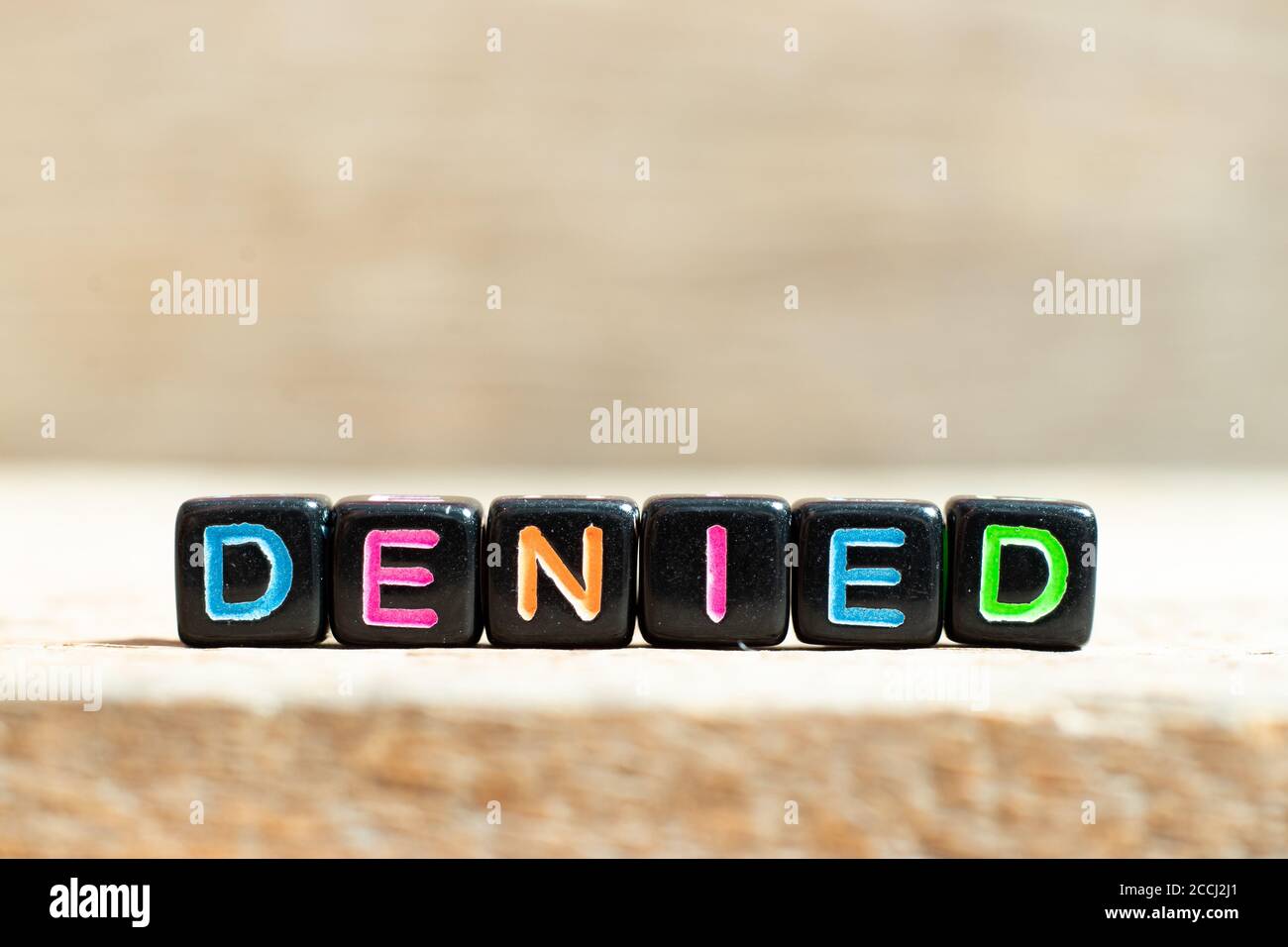 Black bead with color letter in word denied on wood background Stock ...