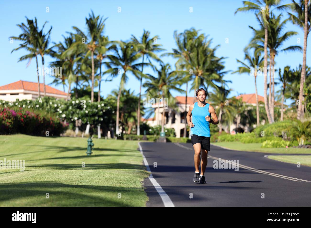 Running man sports fitness athlete runner jogging on residential road ...