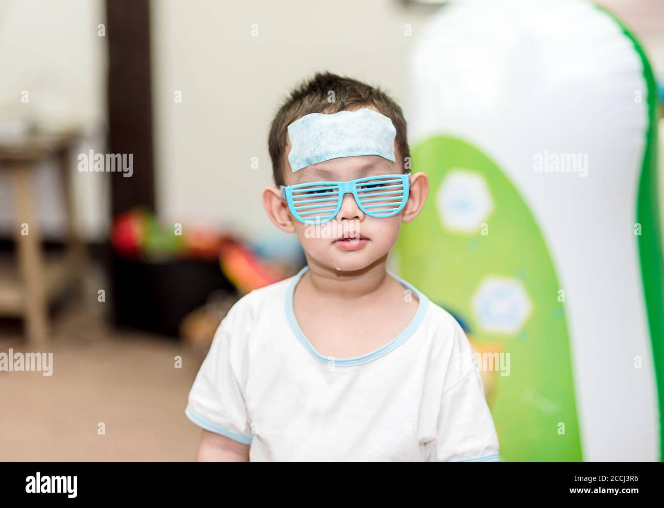 Asian boy having fever . The kid attach cooling gel pad on his forehead ...