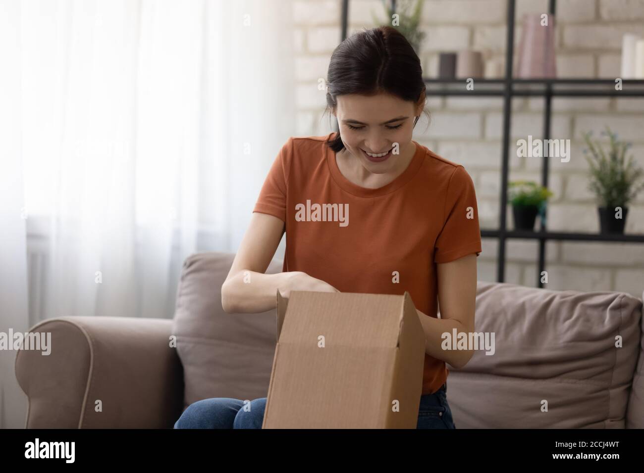 Smiling girl unpack postal box with internet order delivery Stock Photo ...