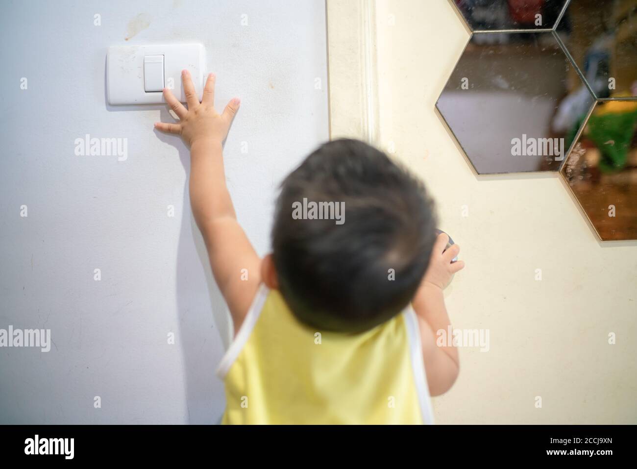 Baby boy playing electric socket lamp plug in room danger child Stock ...