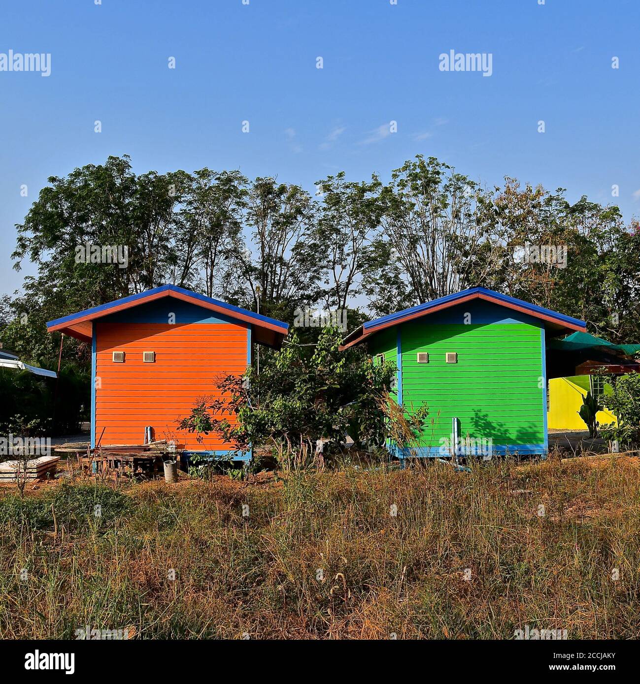 Two colourful rustic wooden cabins painted in bright orange and green ...