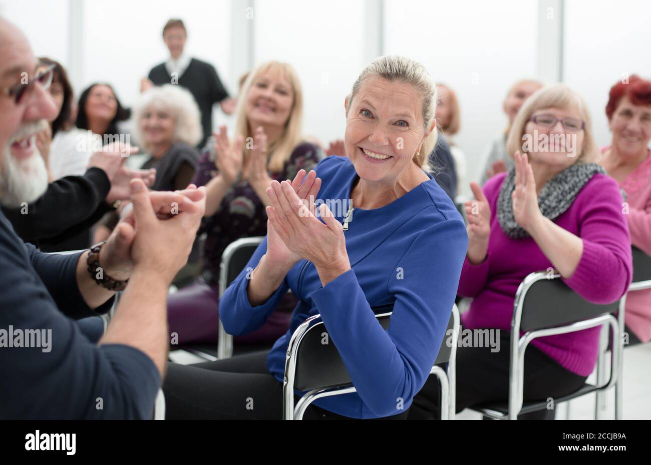 a group of elderly people are sitting in a circle clapping their Stock ...