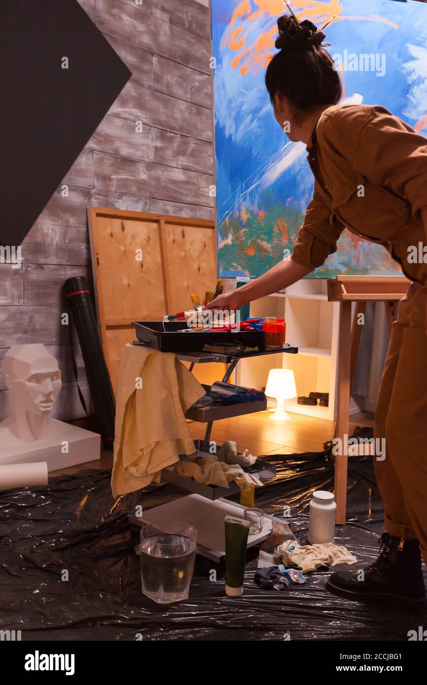 Artist holding paint brush in art workshop in front of large canvas ...