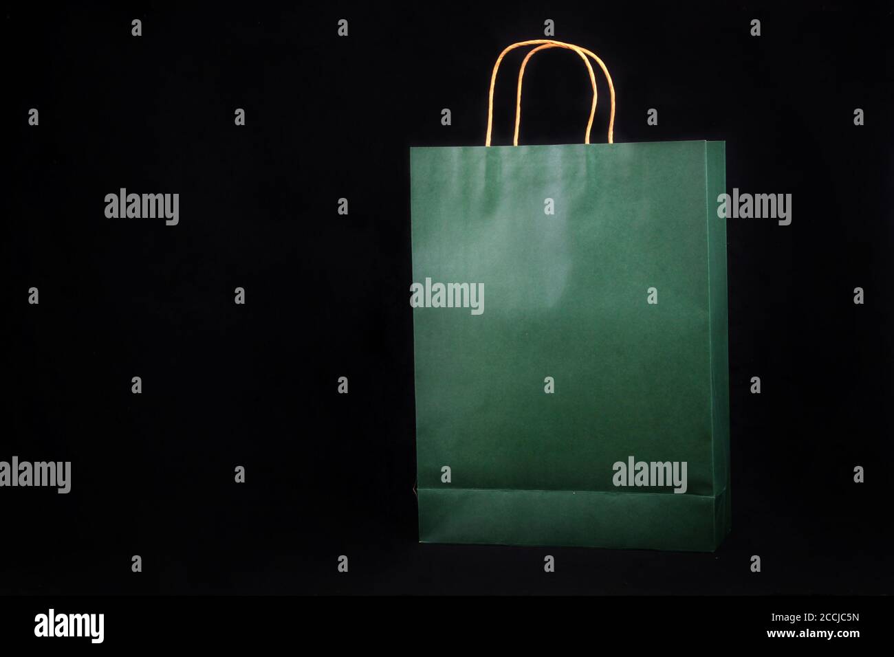 Plain green paper bag packaging on a black background Stock Photo - Alamy