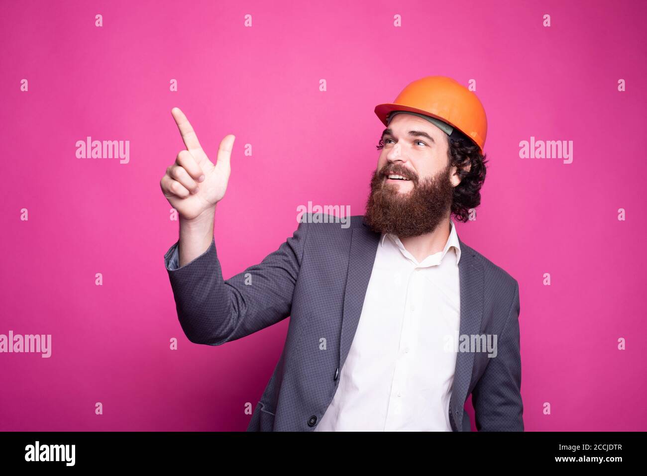 Photo of young engineer man pointing away over pink background Stock ...