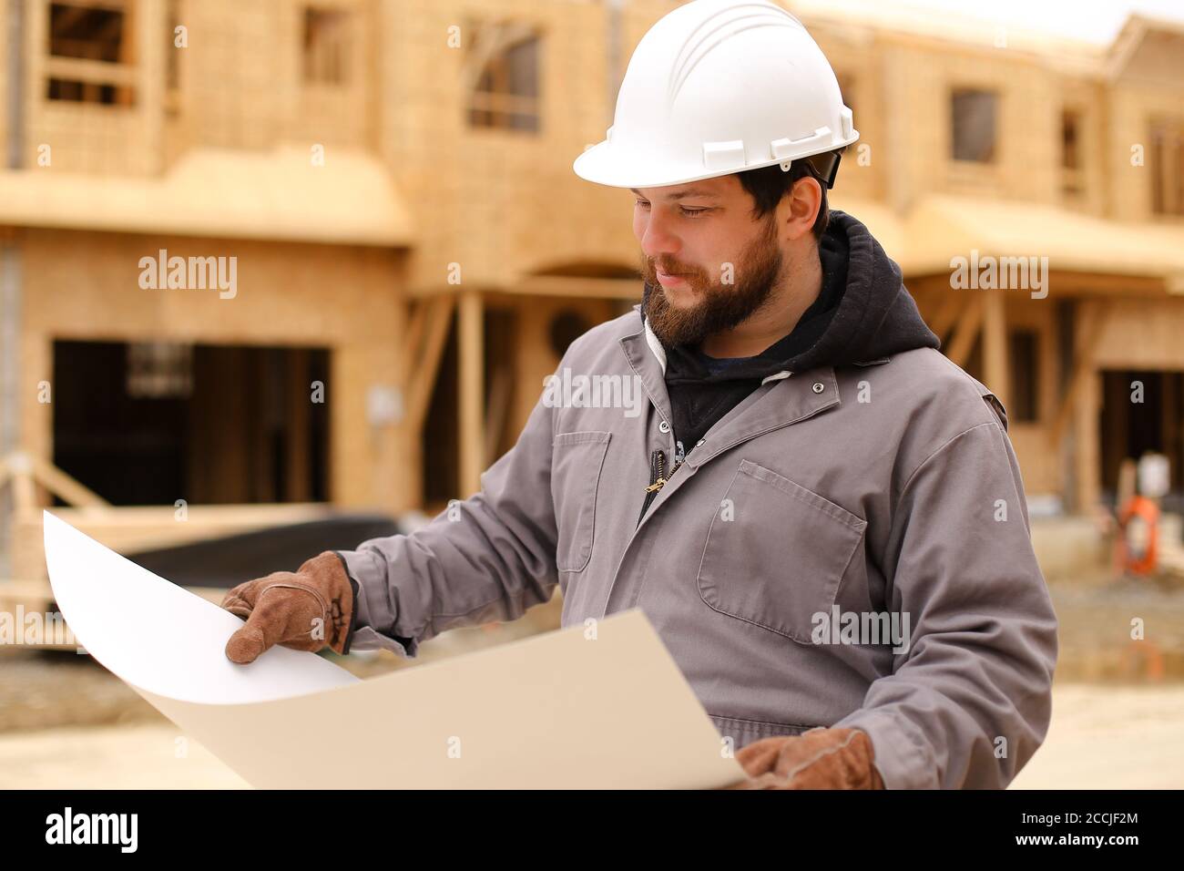 Builder looking at architectural drawing plan on paper at construction ...