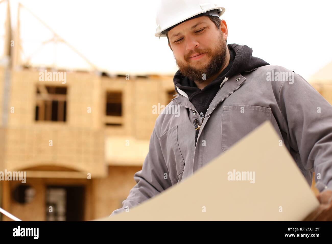 Portrait of builder looking at architectural drawing plan on paper at ...