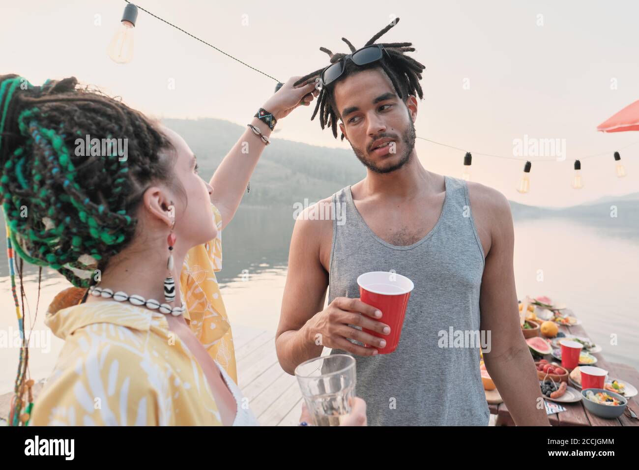 Young woman examining the hairstyle of her boyfriend while they ...
