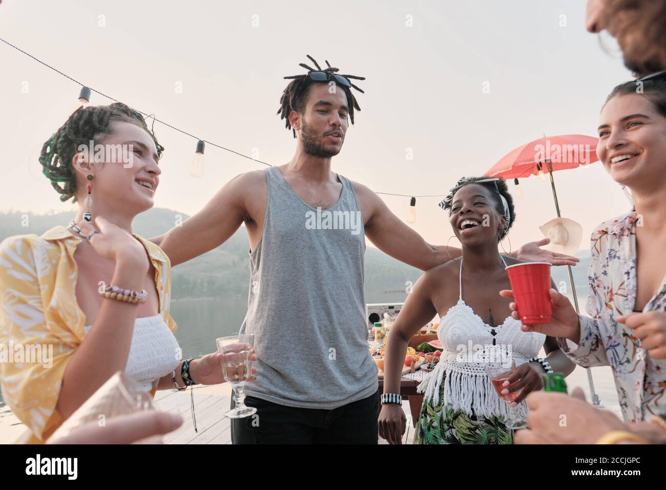 Group of happy young people talking to each other and laughing while ...