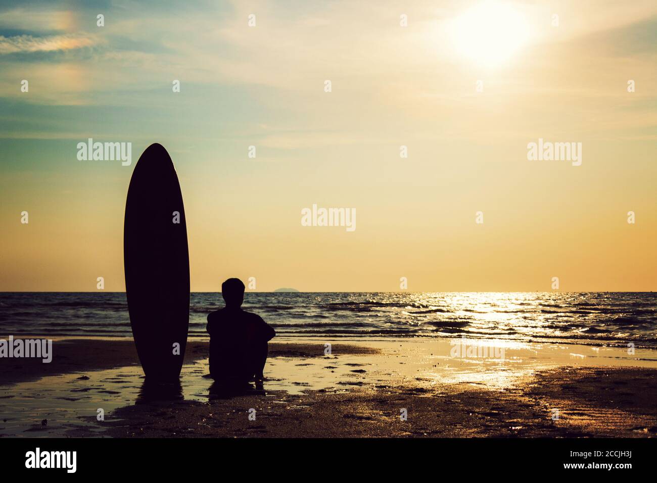 Silhouette of surf man sitting with a surfboard on the seashore beach ...