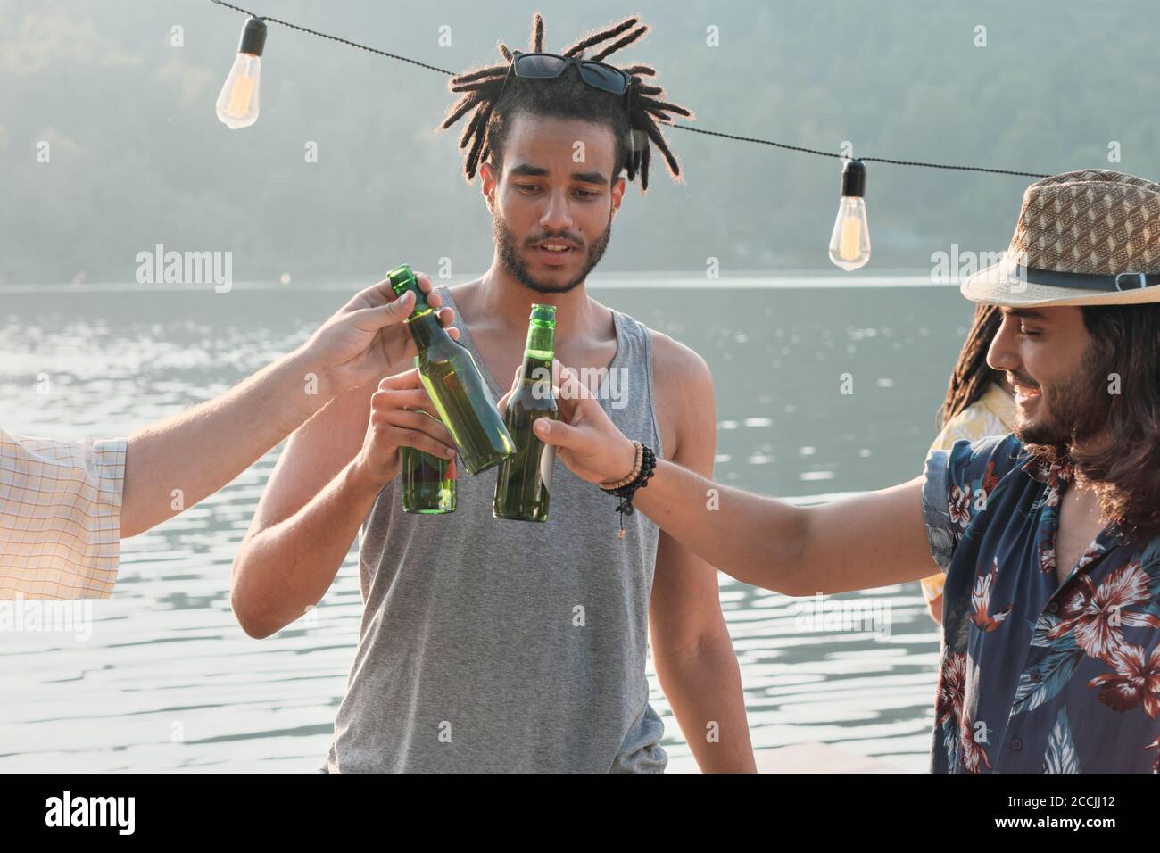 Group of guys toasting with bottles of beer and having fun at party ...