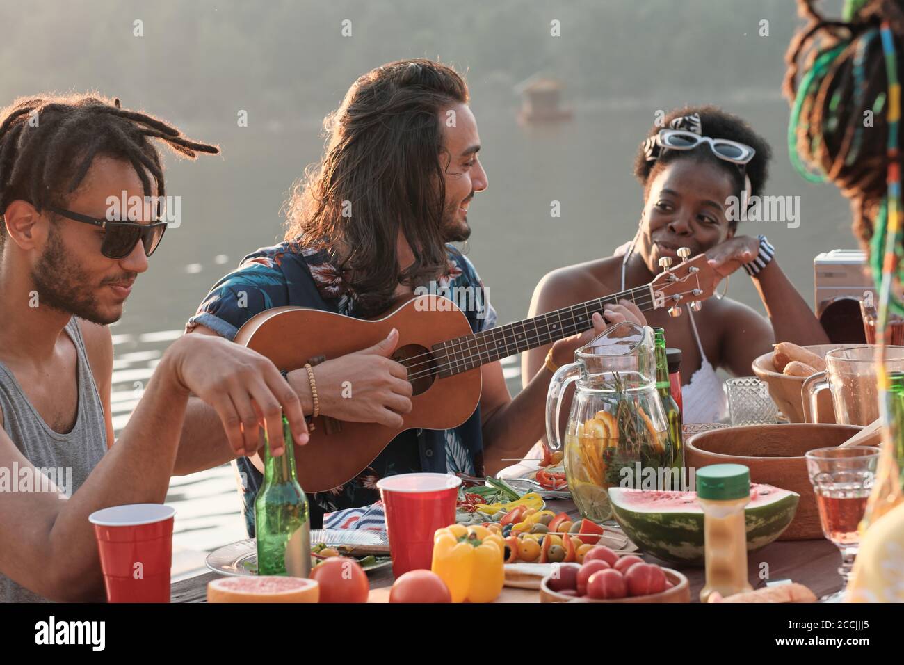 Group of young people playing on guitar and singing while sitting at ...