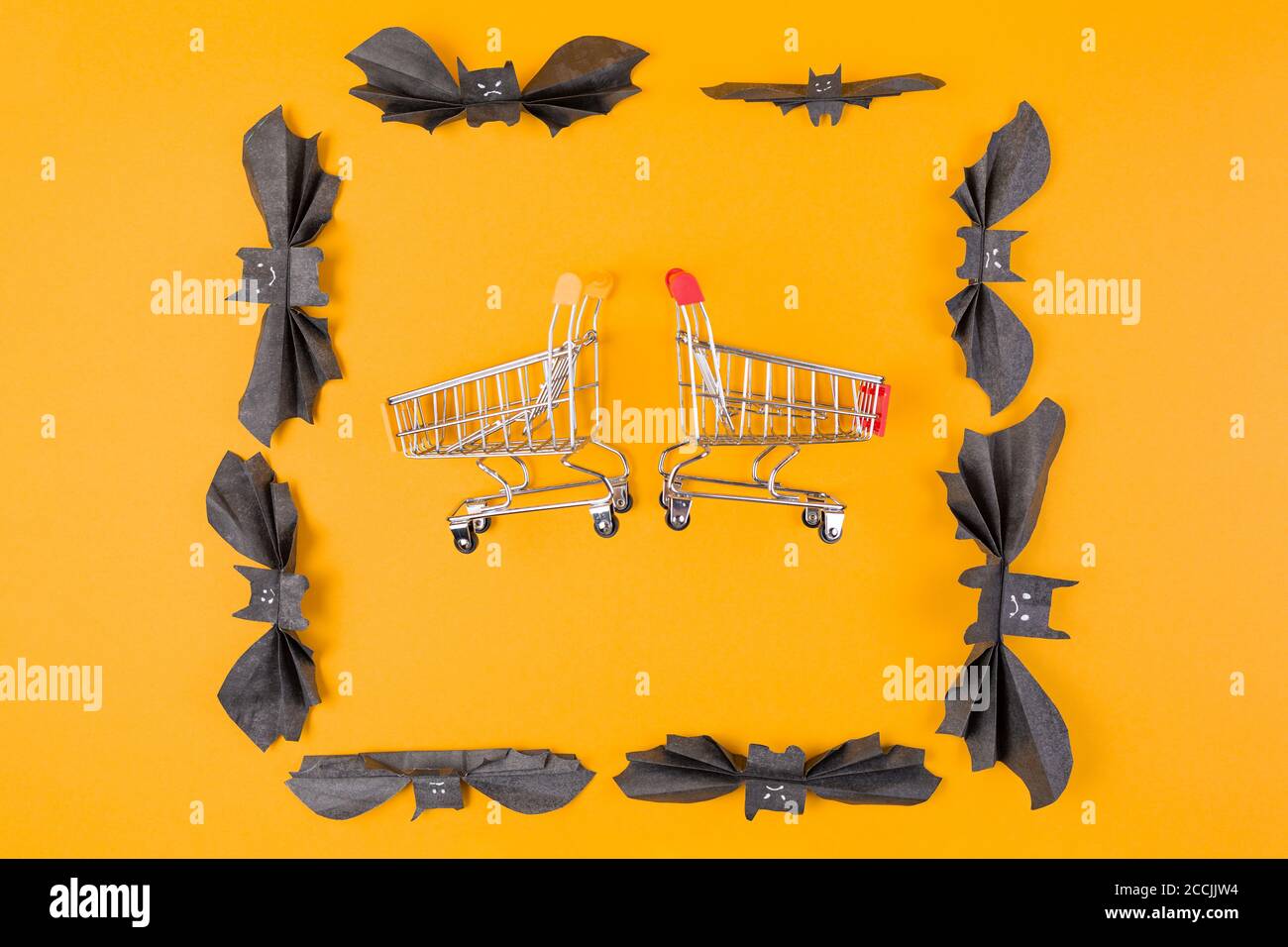 Two shopping mini carts are located in a frame of paper decorative bats ...