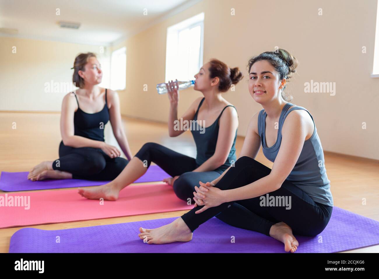 A group of young women resting on mats after training. The concept of ...