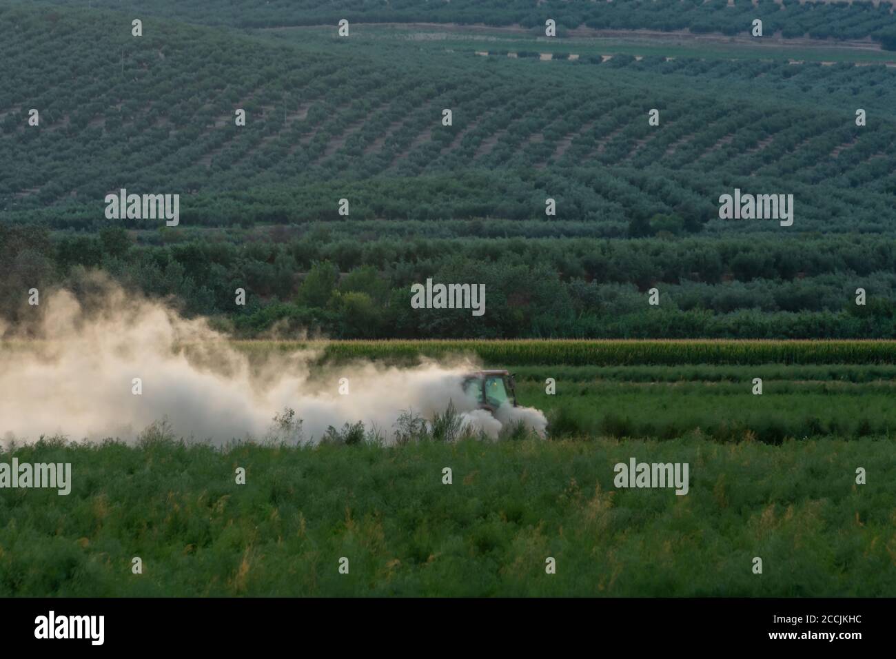 Farm tractor tilling the land and kicking up a lot of dust Stock Photo ...