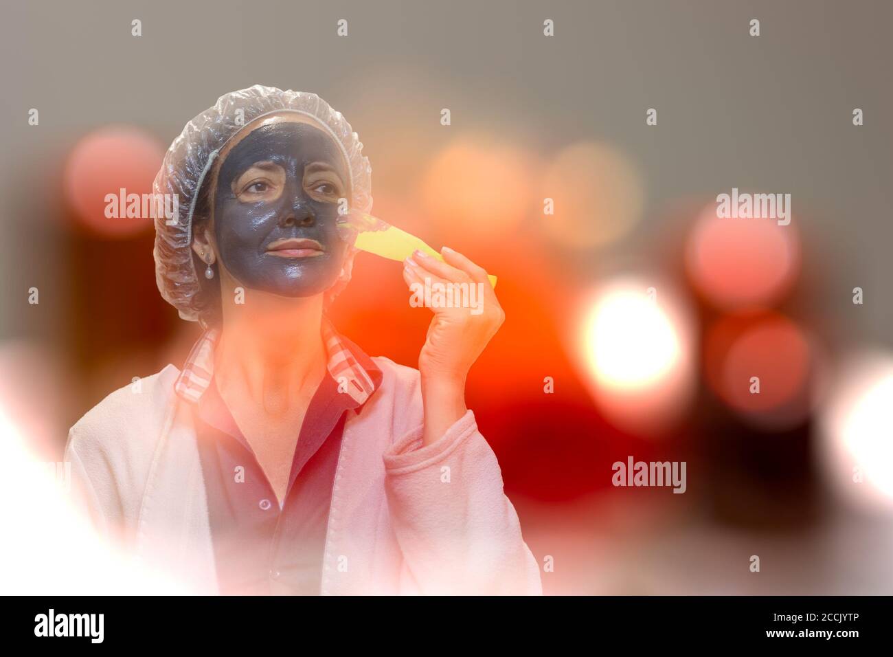Woman doing a mud mask on her face with a scoop Stock Photo - Alamy