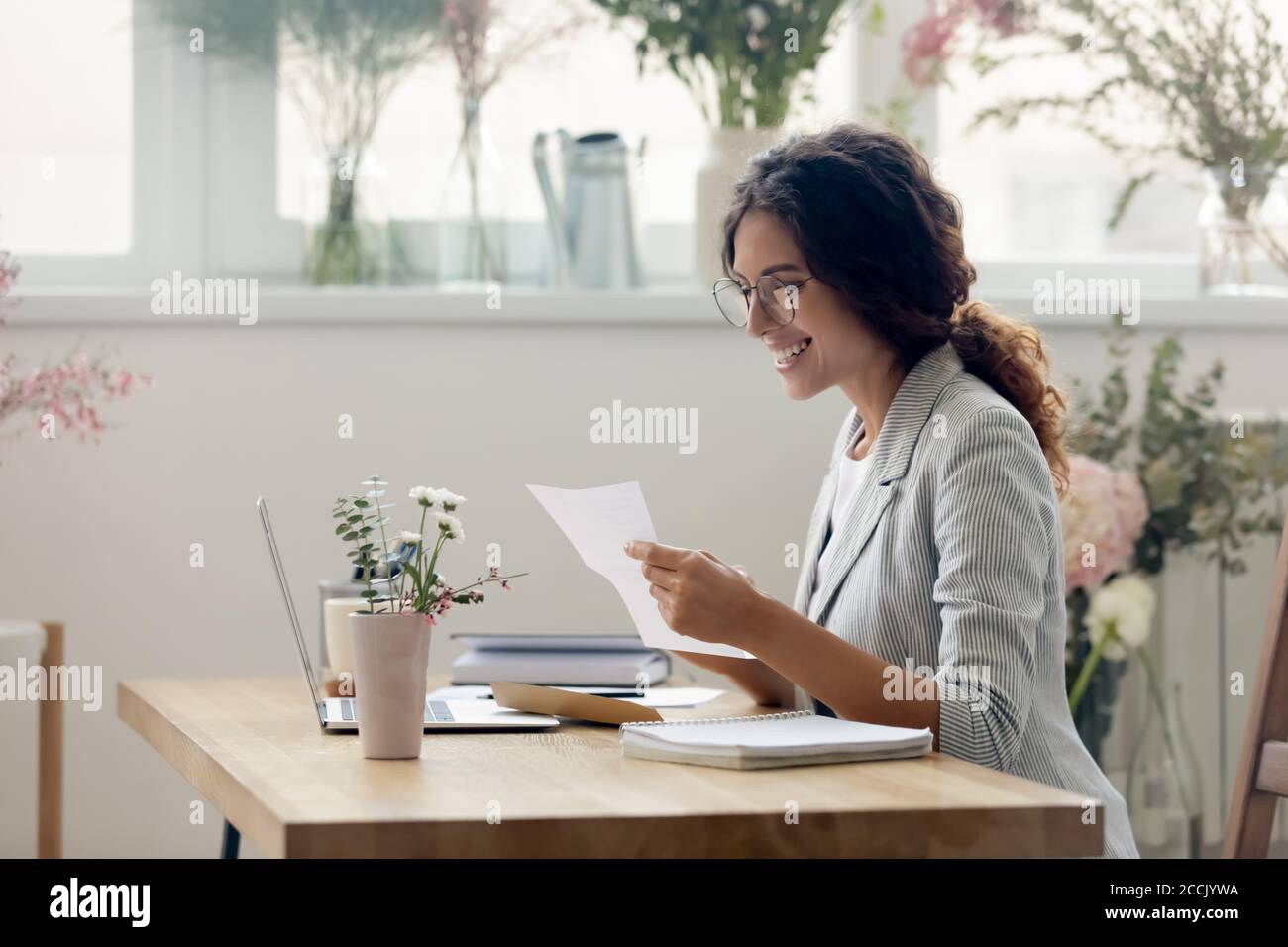 Smiling young businesswoman reading paper letter correspondence Stock ...
