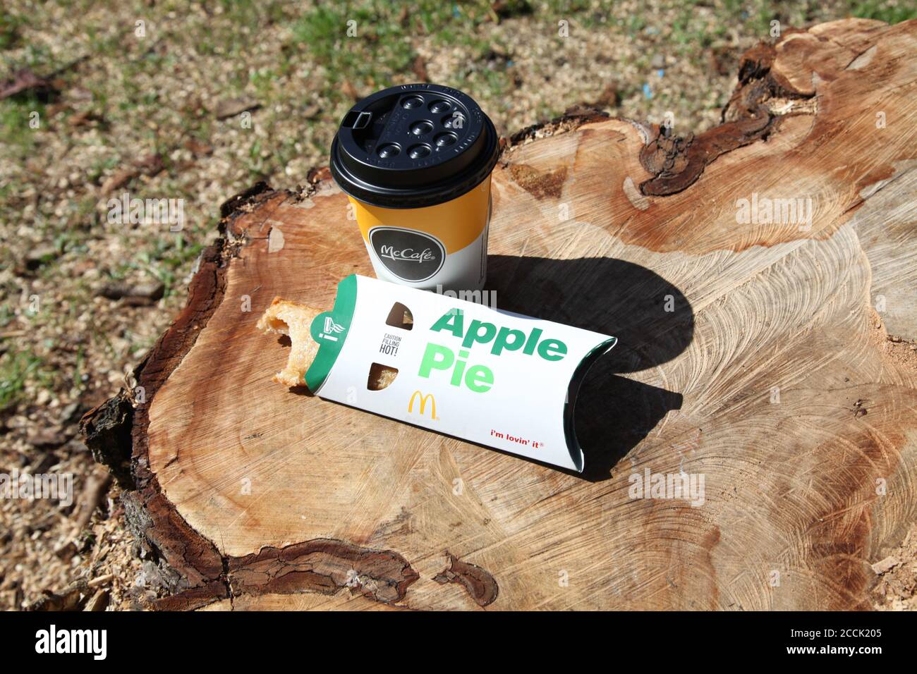 McDonald's Apple Pie (bitten) and McCafe coffee cup outside, sunny day ...