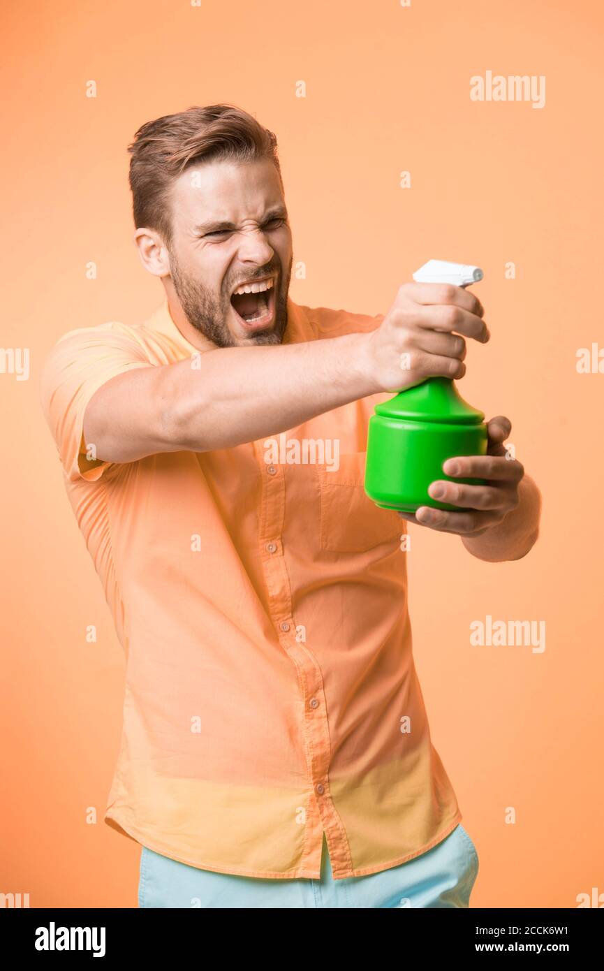 Macho hold plastic spray bottle as gun yellow background. Guy with ...