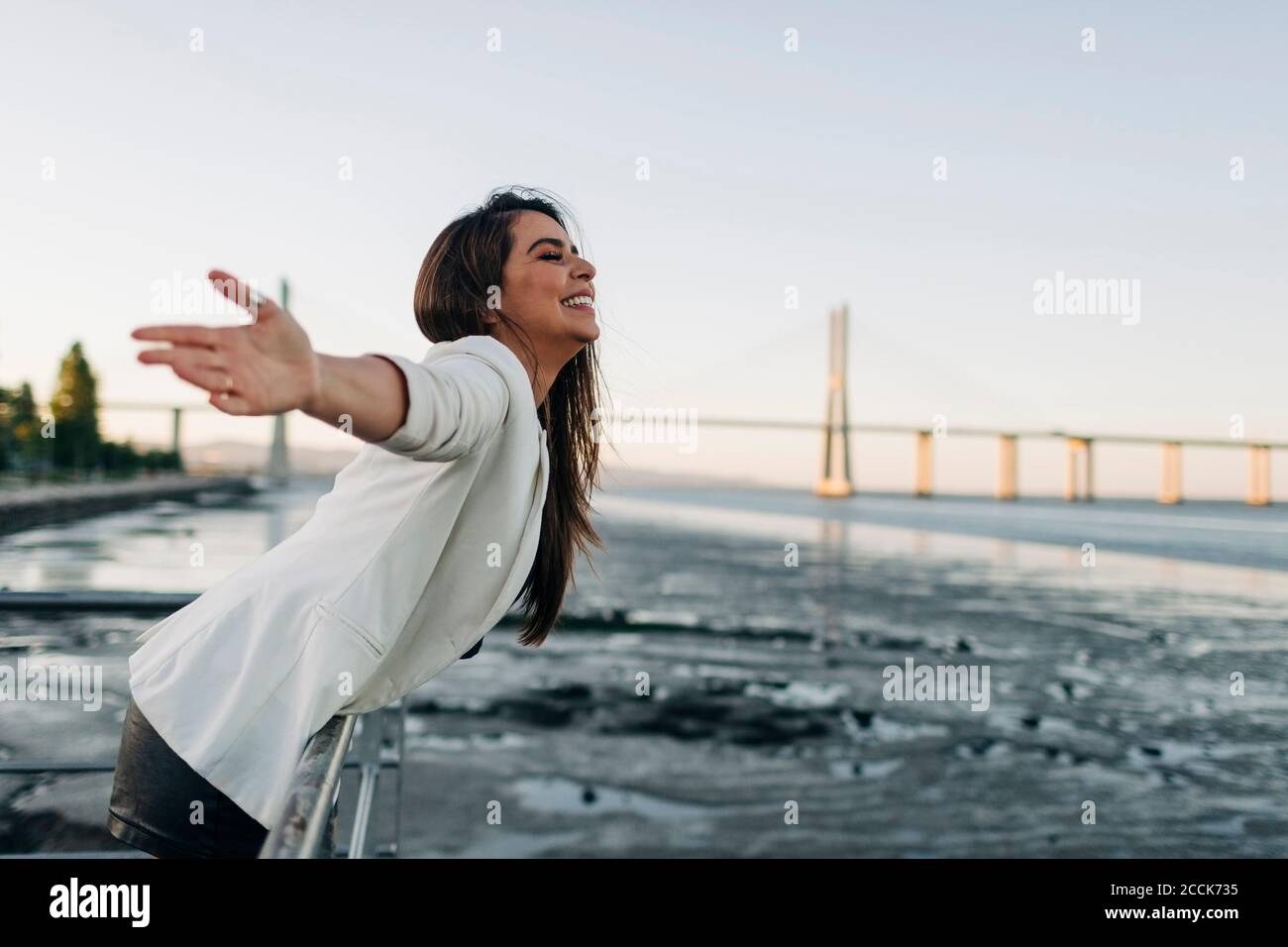 Young woman with open arms standing at riverside Stock Photo - Alamy