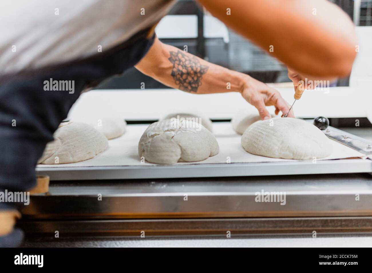 Baker carving shape on bread at bakery Stock Photo - Alamy